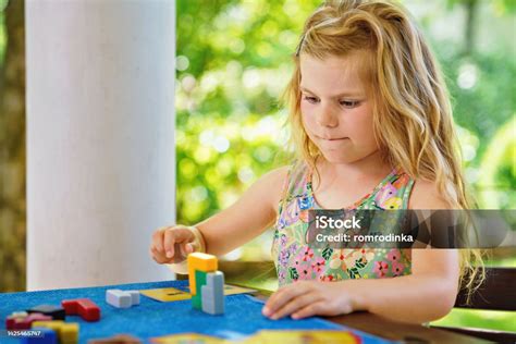 화려한 벽돌로 보드 게임을하는 어린 미취학 소녀 행복한 아이는 나무 블록의 타워를 구축 훌륭한 운동 기술을 개발 홈 조인트 게임 집에서 아이들을위한 여가 활동 가정 생활에