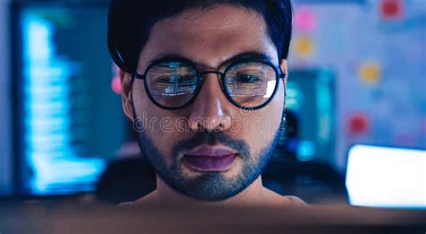 Close-up of a Programmer Intensely Focused on His Work, with Computer Code Reflecting in His ...