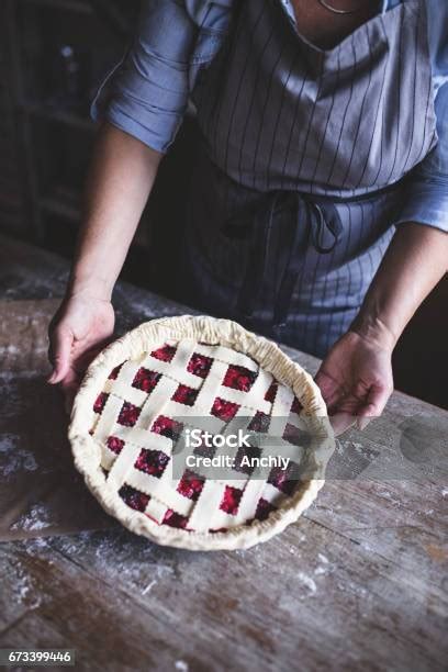 맛 있는 수 제 체리 파이 준비에 대 한 굽기 여 자가 그녀의 손 나무 테이블에에서 파이 들고 격자 파이에 대한 스톡 사진 및