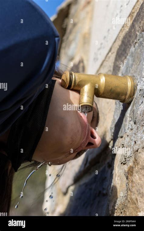 A Mature Male Opening A Metal Water Spout From A Brick Wall Revealing A Stream Of Fresh Water