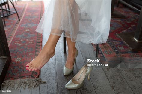 신부의 발 빨간 페디큐어로 여자의 발에 물집이 생깁니다 맨발로 한 발 굽 높은 신발이 옆에 서 있습니다 불편한 신발 피곤하고