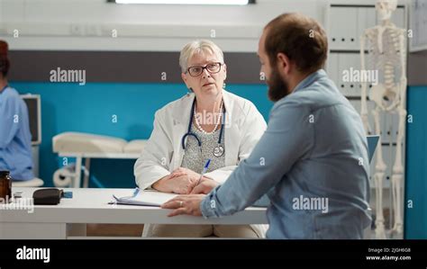 Male Patient Signing Checkup Appointment Report On Papers To Receive