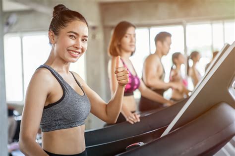 스포츠 체육관에서 러닝 머신에서 달리는 젊은 이들의 그룹 Fitness 여자 주자 쇼 엄지 손가락 에 실행 중인 기계에 아침