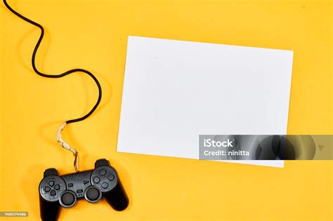 Black Joystick Game Controller With With Blank White Paper On Yellow