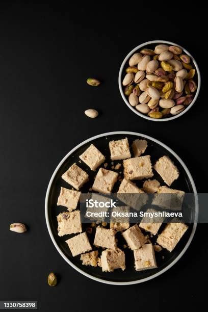 검은 색 배경에 피스타치오를 가진 유기농 할바 전통적인 중동 과자 유대인 터키어 아랍어 국가 디저트 Â 터키어 기쁨 개념 천연 비건 제품 맨 위 보기입니다 공간을 복사합니다