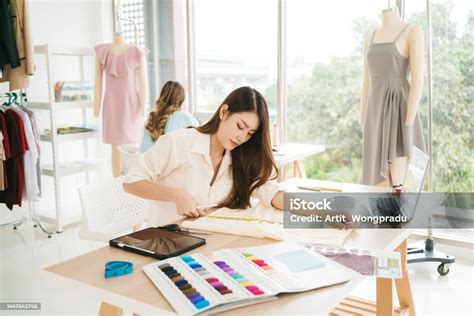 아시아 여성 패션 디자이너 또는 옷 패턴을 만들기 위한 측정 테이프가 있는 재단사 손 측정 종이 새로운 컬렉션을 위해 일하는 워크샵의 패션 디자이너 재단사 가위에 대한 스톡