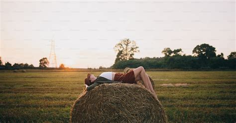 모자를 쓴 아름다운 평온한 여자는 여름 들판에서 저녁을 즐기는 일몰 빛 속에서 건초 더미에 누워 있습니다 시골의 건초 더미에서