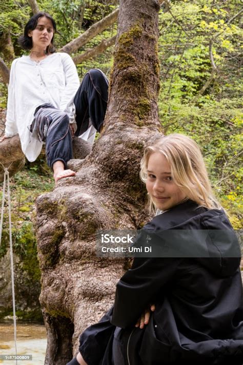 Zwei Mädchen In Schwarzweißen Kleidern Sitzen Auf Einem Baum Stockfoto