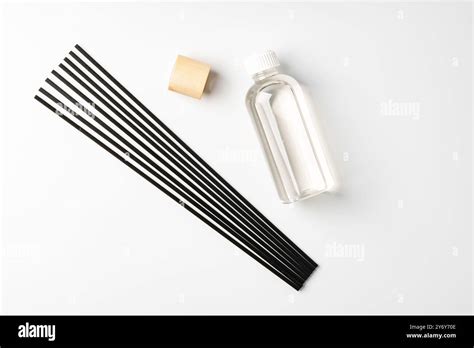 A Minimalist Display Of Essential Oil And Black Diffuser Sticks On A Clean White Background