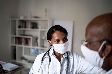 여성 의사는 의료 약속 중에 수석 환자를 위로 얼굴 마스크를 사용하여 아프리카 민족에 대한 스톡 사진 및 기타 이미지 아프리카 민족 환자 손을 어깨에 두기 Istock