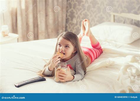 Маленькая девочка ест печенья овсяной каши в кровати Стоковое Фото изображение насчитывающей