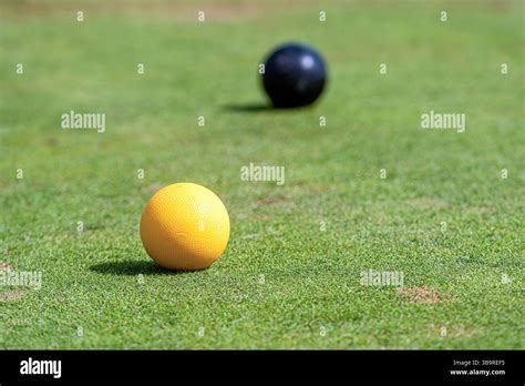Colorful Balls Rest On A Well Maintained Lawn As Players Get Ready For