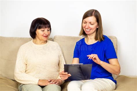 Joven Cuidador Que Muestra La Receta O El Documento Y Ayuda A Ancianas En Casa Imagen De