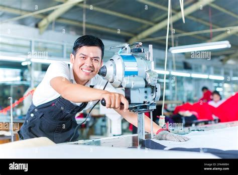 Indonesian Worker Using A Cutter A Large Machine For Cutting Fabrics