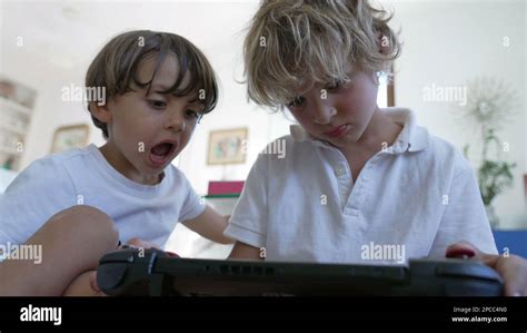 Two Small Boys Looking At Video Game Screen Tablet Younger Brother