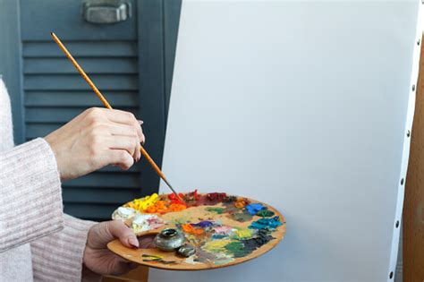 흰색 캔버스에 대 한 멀티 컬러 아크릴 페인트와 팔레트 브러쉬를 들고 분홍색 스웨터에 여성의 손의 클로즈업 개념에 대한 스톡