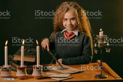 검은 연기가 자욱한 배경에 테이블에 앉아 어두운 옷을 입고 작은 마녀 마법의 지팡이 주문이있는 책 촛불이 있습니다 가을에 대한 스톡 사진 및 기타 이미지 Istock