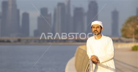 رجل عربي خليجي إماراتي، بالزي الإماراتي التقليدي، خلفية ضبابية لأبراج