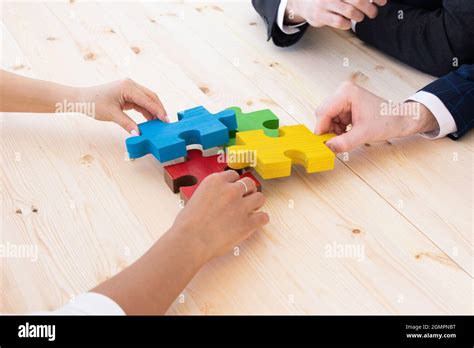 business people team assembling four color jigsaw puzzle pieces unity