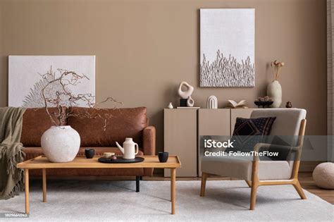 모형 포스터 프레임 갈색 소파 회색 안락 의자 나무 커피 테이블 베이지 카펫 및 개인 액세서리가있는 아늑한 거실 인테리어의 인테리어 디자인 가정 장식 템플렛 0명에 대한