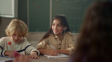Students Learning At Round Table In School Pupils Writing Text In
