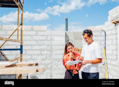 Man Architect Engineer Showing House Under Construction To Woman Future Homeowner Checking