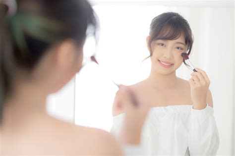 침실에 브러쉬 뺨으로 메이크업을 적용 얼굴을 찾고 거울 블러셔 스킨 케어 및 화장품 테이블 패션 개념을 들고 아름다운 여자와 미소 뷰티 초상화 젊은 아시아 여성 귀여운에