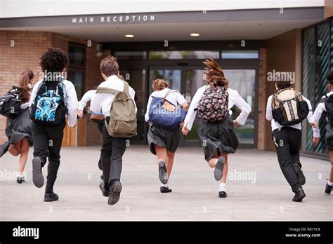Group Of High School Students Wearing Uniform Running Into School