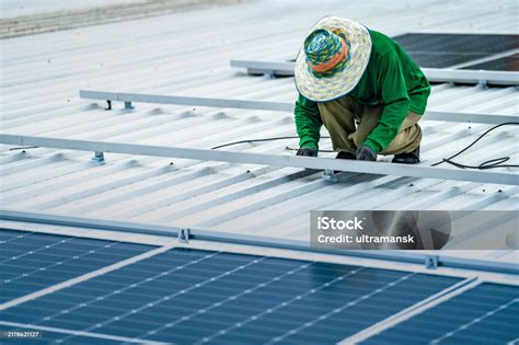 작업자가 옥상에 태양 전지판을 설치하거나 유지 관리합니다 이 이미지는 재생 에너지 기술 태양광 발전 시스템 및 지속 가능한 에너지 솔루션을 구현하는 데 있어 작업자의 역할을