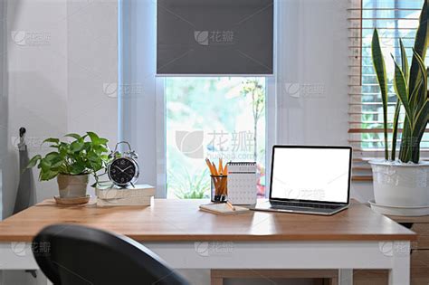 电脑笔记本、日历、笔记本、闹钟放在木桌上。