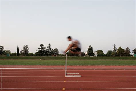 Unrecognizable Sportsman Leaping Over Hurdle In Evening By Stocksy Contributor Milles Studio