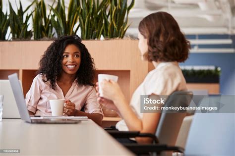 테이블에서 일 하는 2 명의 사업가 현대 오픈 플랜 사무실에서 커피를 함께 마시는 말하기에 대한 스톡 사진 및 기타 이미지