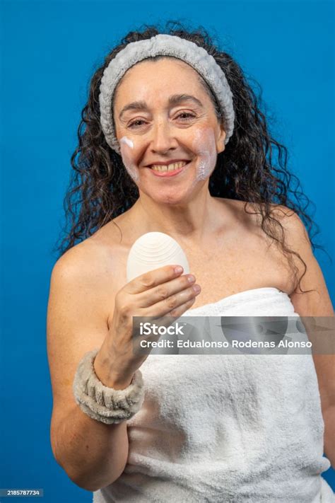 샤워 후 수건을 착용하고 얼굴 클렌징 브러시를 들고 웃는 여자 55 59세에 대한 스톡 사진 및 기타 이미지 55 59세 각질제거 건강한 생활방식 Istock
