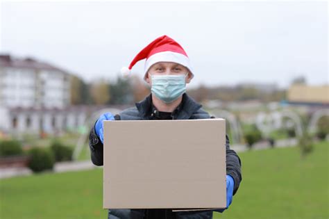 보호 마스크 장갑 산타모자를 들고 있는 배달원 야외에서 손에 상자를 들고 휴일 시간에 코로나바이러스 중 배달 서비스 30 34세에 대한 스톡 사진 및 기타 이미지 Istock