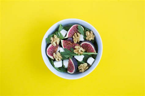 노란색 배경의 흰색 그릇에 Arugula Feta 치즈 무화과 및 호두를 곁들인 샐러드 상단 보기 공간을 복사합니다 노란색 배경에 대한 스톡 사진 및 기타 이미지 Istock