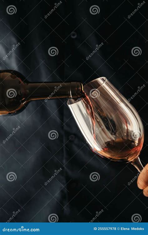 le nom d un sommelier qui verse du vin rouge d une bouteille dans un
