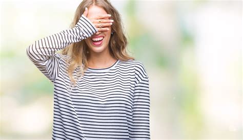 아름 다운 젊은 금발 여자 놀람에 대 한 눈을 덮고 얼굴에 손으로 웃 고 웃 고 고립 된 배경 위에 줄무늬 스웨터를 입고 눈 먼