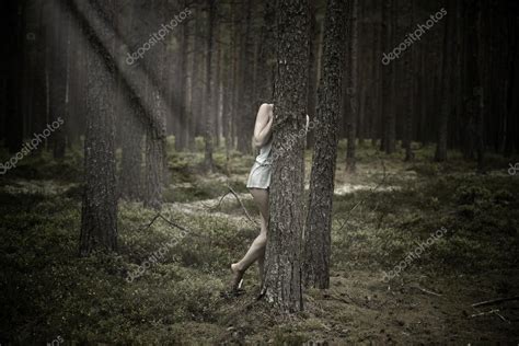 Beautiful Woman Hiding Behind A Tree In The Forest Stock Photo By