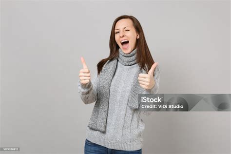 회색 스웨터에 밝은 젊은 여성이 보여주는 엄지손가락 회색 벽 배경에 고립 점멸 스카프 건강 패션 라이프 스타일 사람들이 진심으 감정 추운 계절 개념 복사 공간을 비웃는 다
