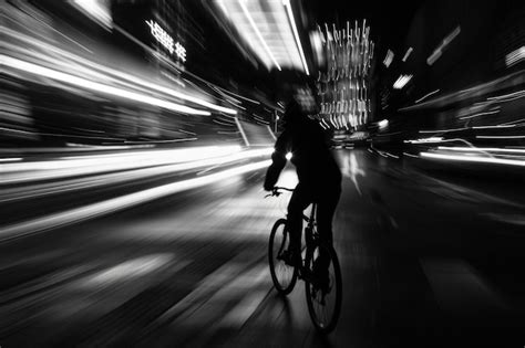 Black And White Blurred Motion Image Of A Cyclist Riding Through A City