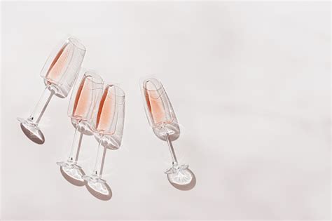 투명한 줄기 안경에 담긴 로즈 와인 미니멀한 스타일의 정물 햇빛과 그림자가 있는 최고의 로즈 샴페인 스파클링 와인 흰색 배경에 여름 가벼운 알코올 음료 복사 공간 0명에