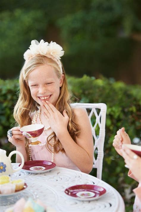 Enjoying A Cup Of Team With Her Friend Two Young Girls Having A Tea Party In The Backyard