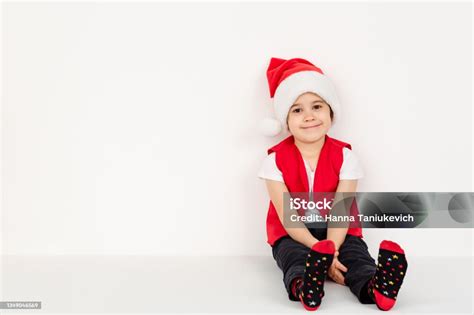흰색 배경에 고립 된 빨간 산타 클로스 모자에 앉아 행복한 미소 아이의 초상화 아름다운 5 년 유럽 소년 기치 공간을 복사합니다 메리 크리스마스 모형 디자인 연말연시 카드