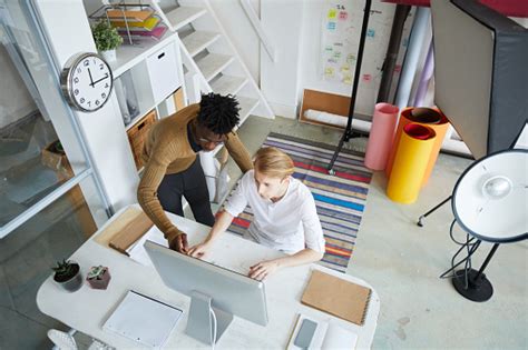 직접 캐주얼 의류에 젊은 멀티 에스닉 사진 작가의 보기 컴퓨터에 사진을 보정 하 고 작은 사진 스튜디오에서 디자인을 논의 바로 위에 대한 스톡 사진 및 기타 이미지 Istock