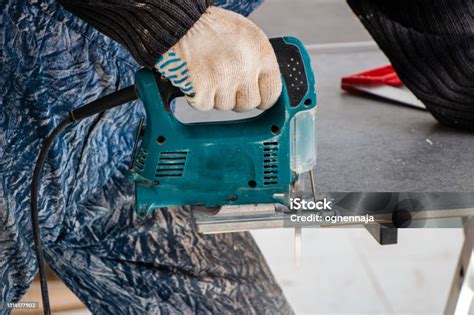 패널에서 전기 손 퍼즐과 건설 노동자 톱질 및 절단 부품의 남성 손 전기 퍼즐로 실내 장식을위한 건물 보드를 절단하는 과정