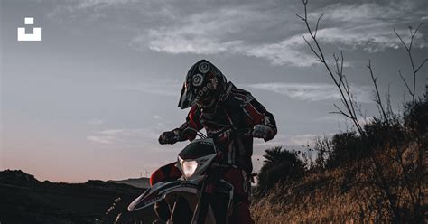 검은 색과 빨간색 오토바이 정장을 입은 남자가 갈색 잔디밭에서 모터 크로스 먼지 자전거를 타고 있습니다 사진 Unsplash의 무료 해질녘 이미지