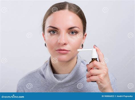 Ragazza Attraente Che Prende Una Medicina Con Spruzzo Dentro La Gola Su Fondo Leggero Fotografia