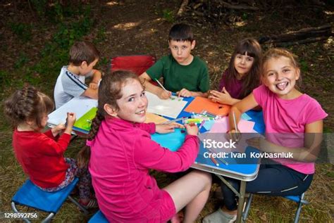 아이들은 자연을 그립니다 파란색 테이블에 색종이와 연필이 많이 있습니다 남자와 여자는 야외에서 재생합니다 공원에서 그리기 교훈 여름에 텐트 캠프에서 휴식을 취하십시오 10