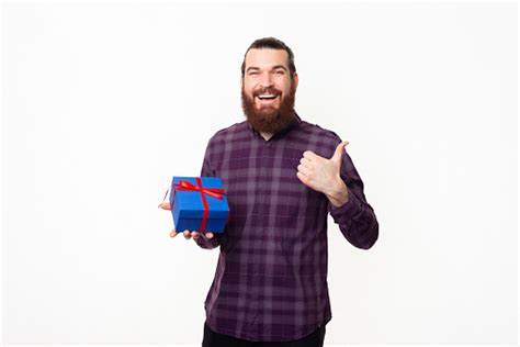 엄지 손가락을 보여주고 파란색 선물 상자를 들고 수염을 가진 행복한 잘 생긴 남자 25 29세에 대한 스톡 사진 및 기타 이미지 25 29세 긍정적인 감정 표현 나무