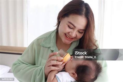 과체중 엄마는 갓 태어난 아기를 팔에 안고 먹이고 어린 아이는 하얀 침실에서 엄마가 들고 있는 병에서 우유를 마시고 사랑스러운 가족 엄마와 아이가 함께 시간을 보내고 부모는